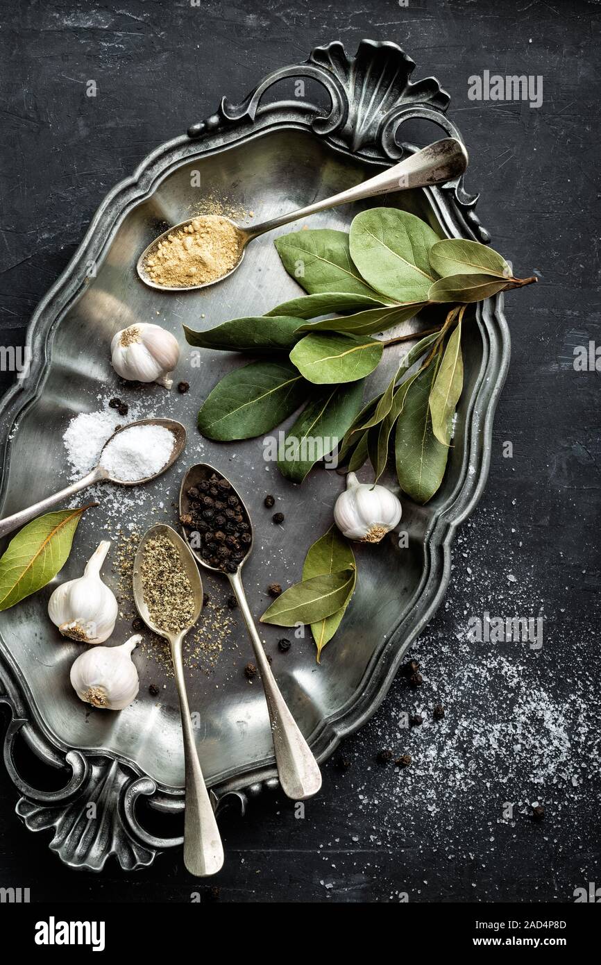 Dark culinary background with bay leaves, salt, pepper and garlic Stock ...