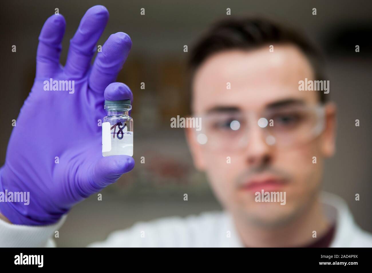Drug manufacturing. Laboratory worker handling a drug vial at a ...