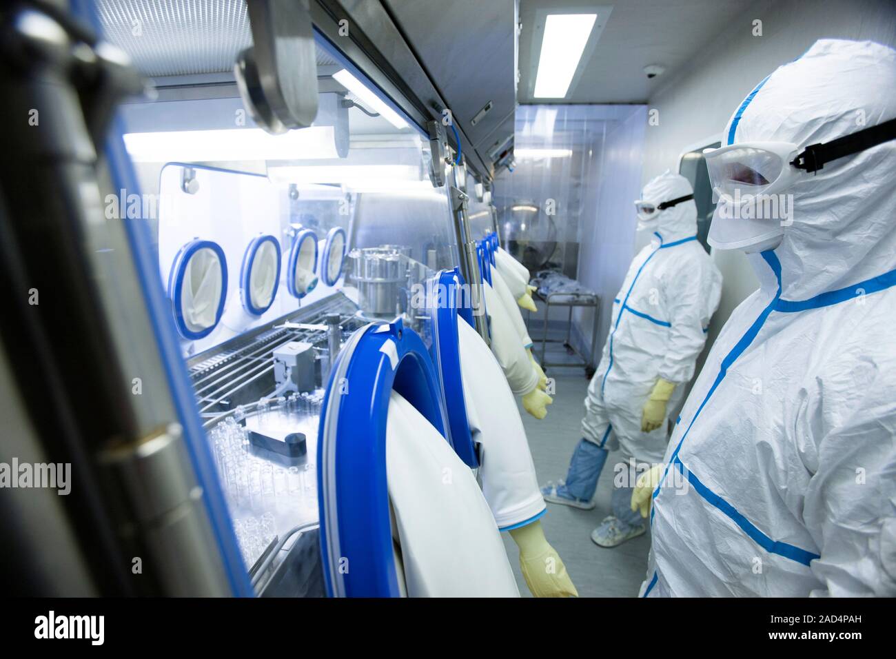 Drug manufacturing. Laboratory workers carrying out aseptic filling of ...