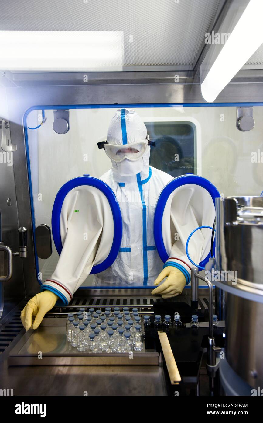 Drug manufacturing. Laboratory worker carrying out aseptic filling of ...