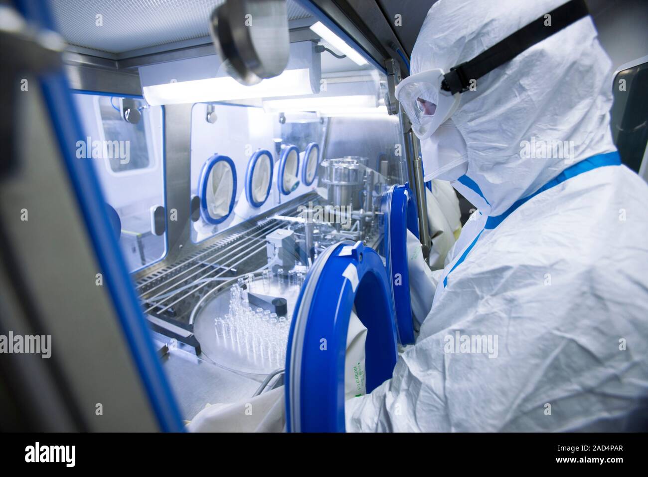 Drug manufacturing. Laboratory worker carrying out aseptic filling of ...