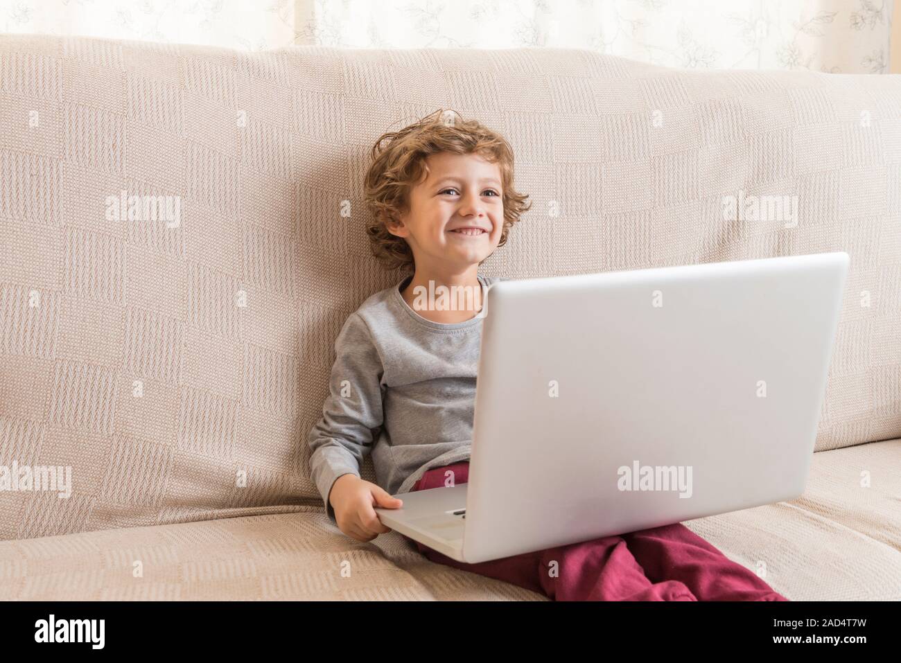 Child sitting on a sofa watching a laptop. Technology concept in ...