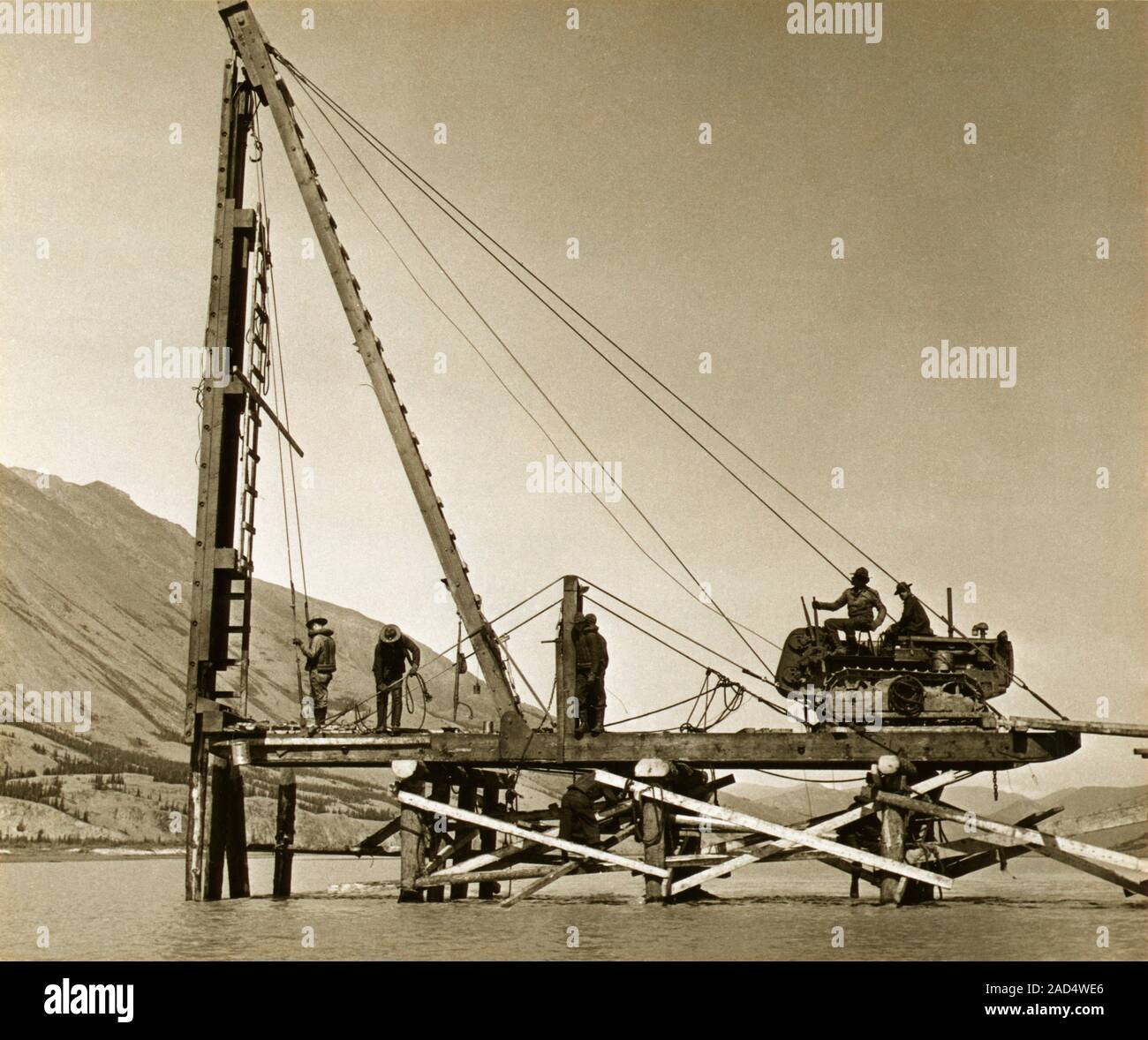 River bridge construction. Pile driver and a caterpillar-tracked ...