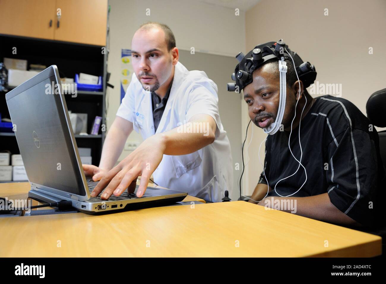 Brain-computer interface research. A researcher works with a patient to ...