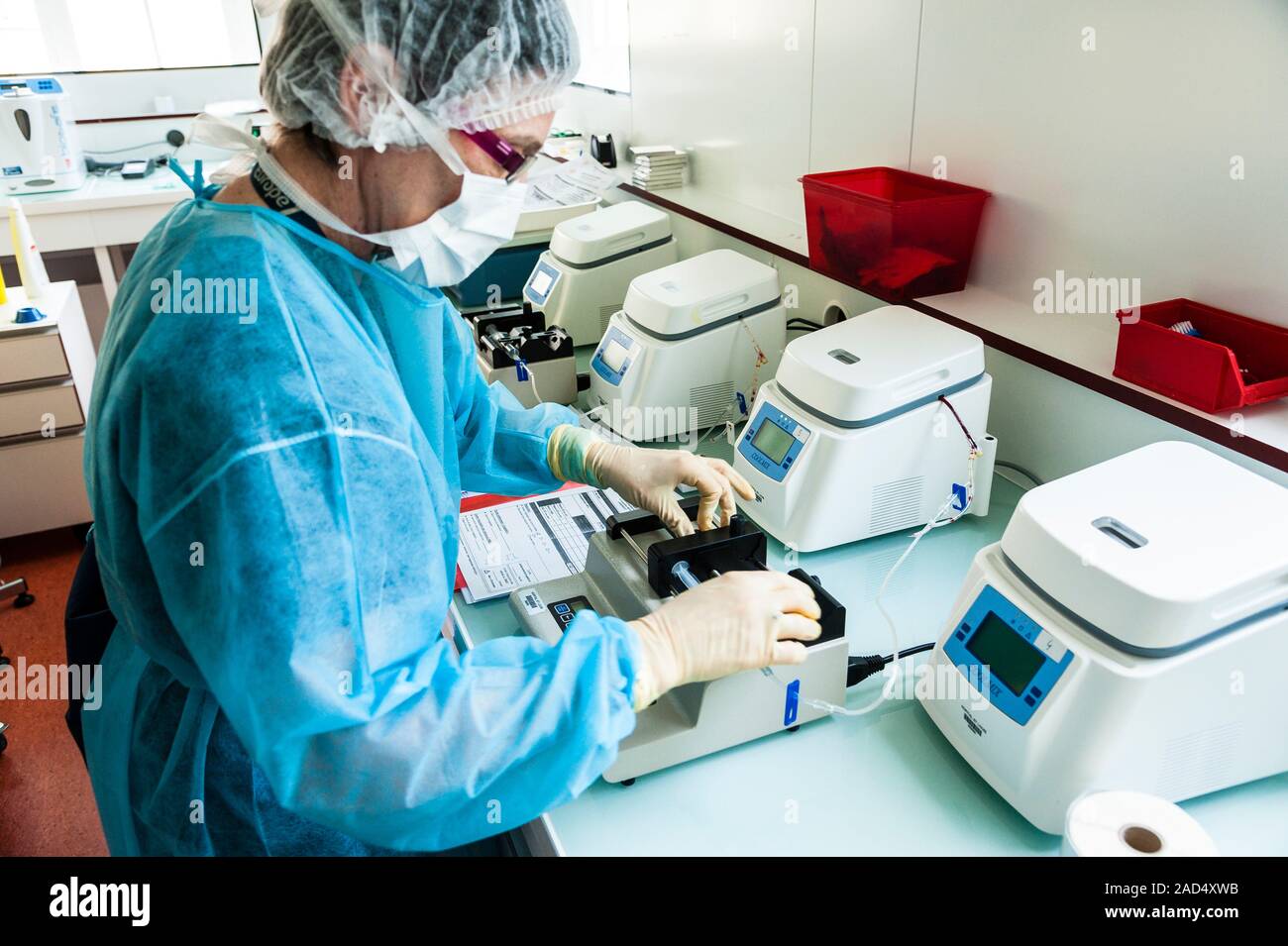 Blood product processing. A technician injects cryoprotectant into ...