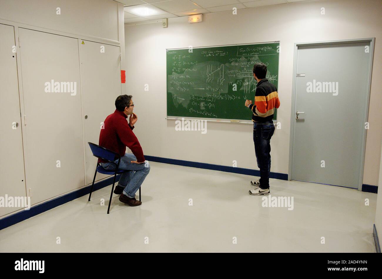 Mathematics. Two men consider mathematical equations written on a ...