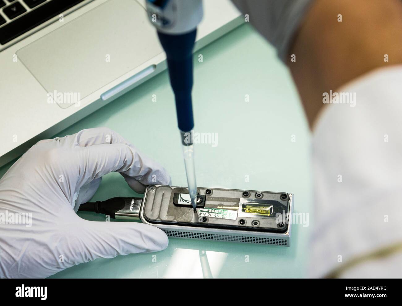 Nanopore sequencing of DNA. A technician injects a fluid into a Minion ...