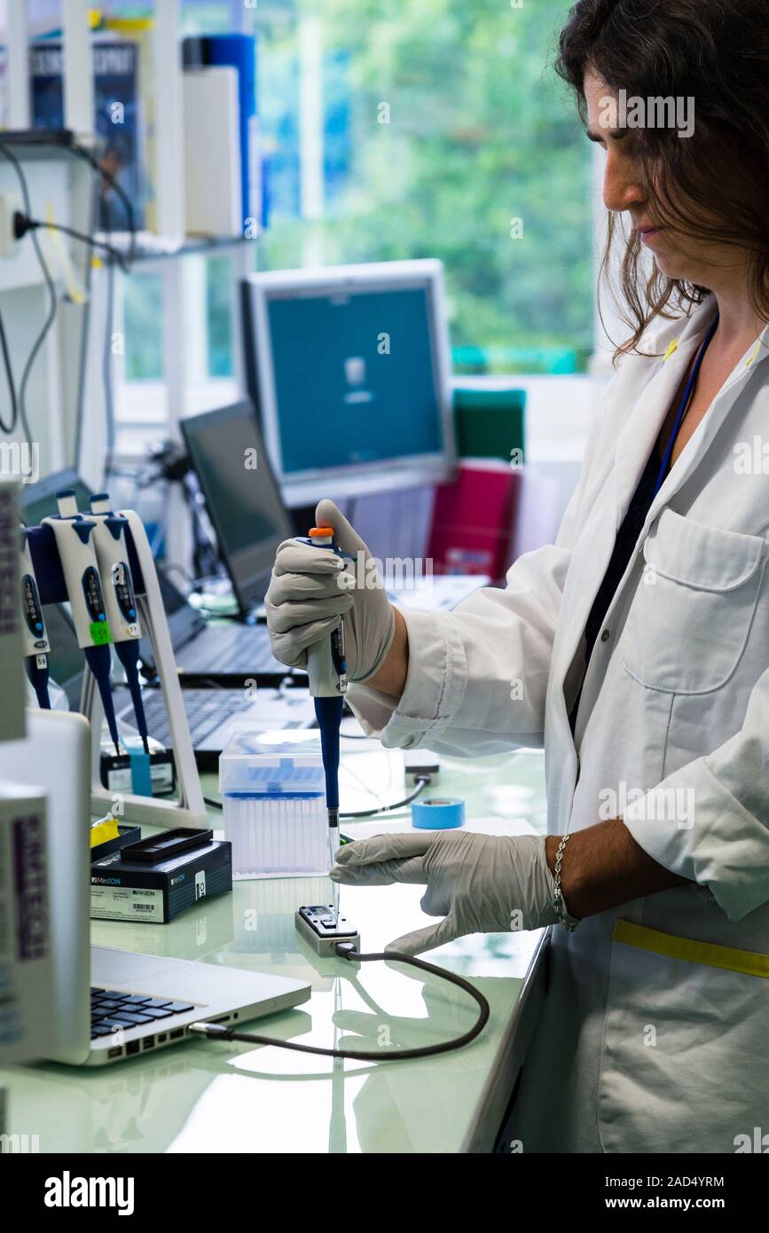Nanopore sequencing of DNA. A technician injects a fluid into a Minion ...