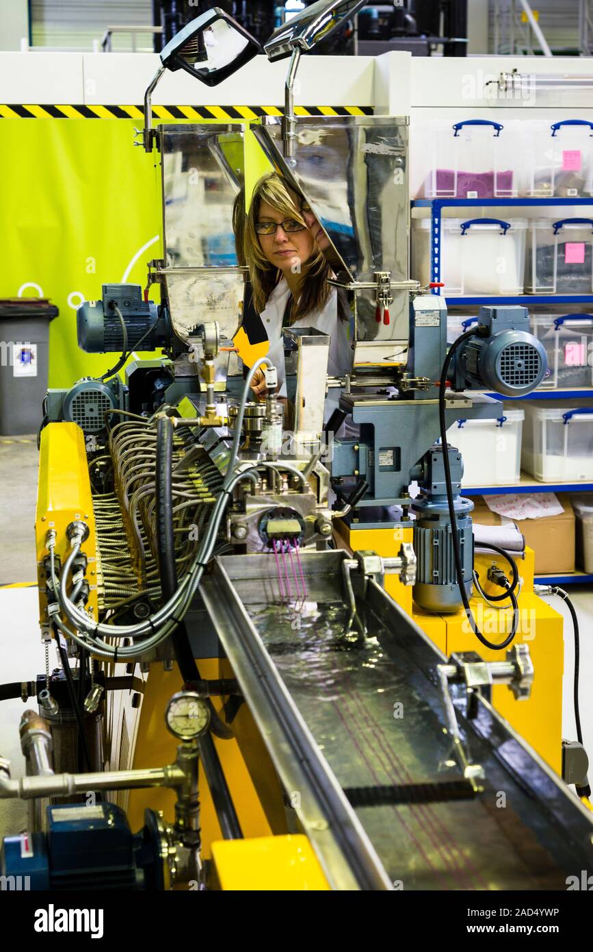 Plastics recycling. A technician oversees a machine which extrudes ...