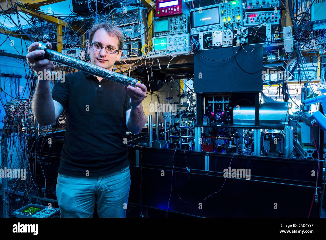 Strontium optical lattice clock research. A researcher holding a tube ...