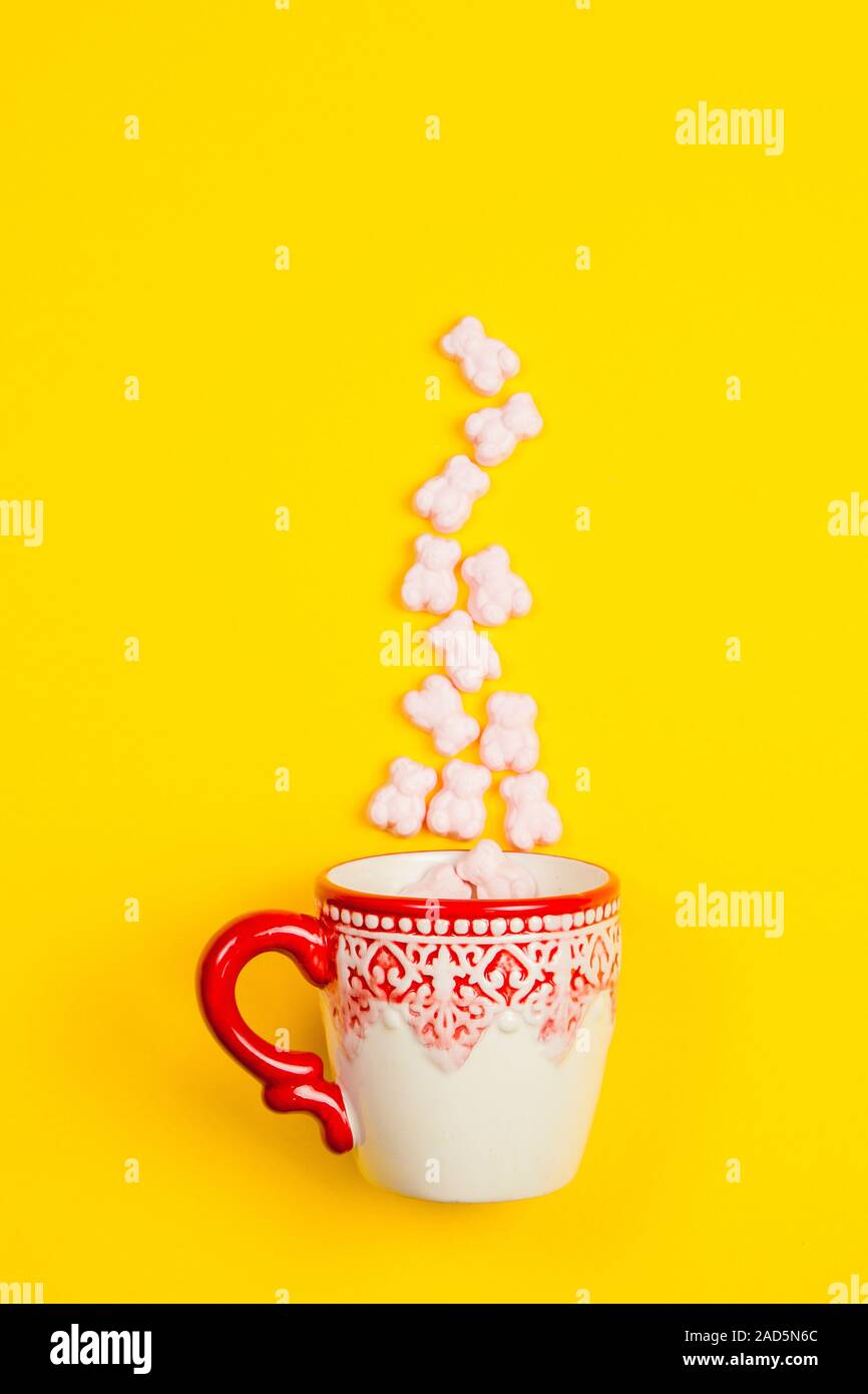 Marshmallows, sugar cubes and candy sticks in a holiday mug on a yellow ...