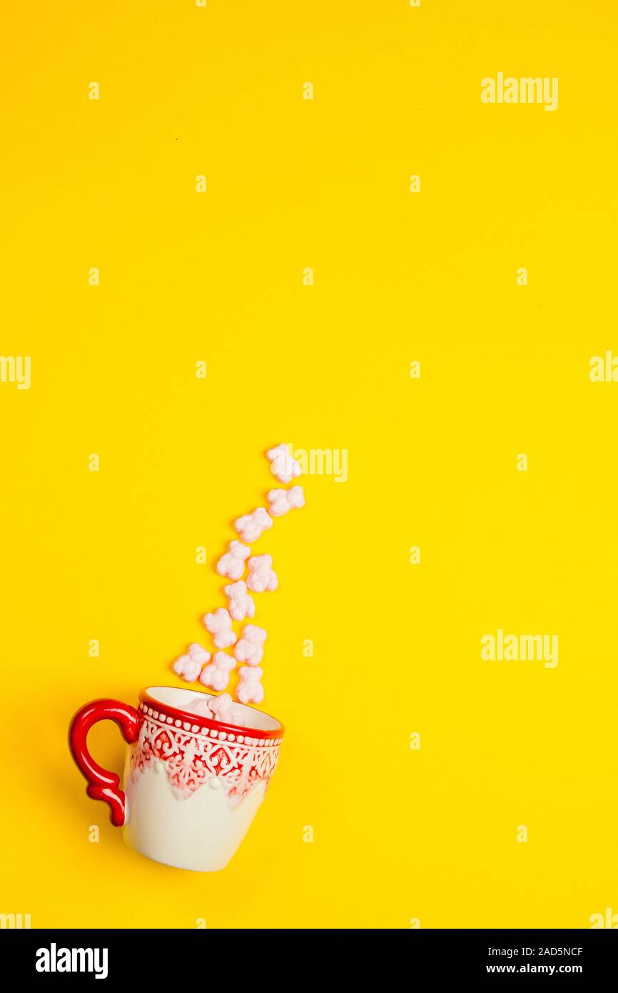 Marshmallows, sugar cubes and candy sticks in a holiday mug on a yellow ...