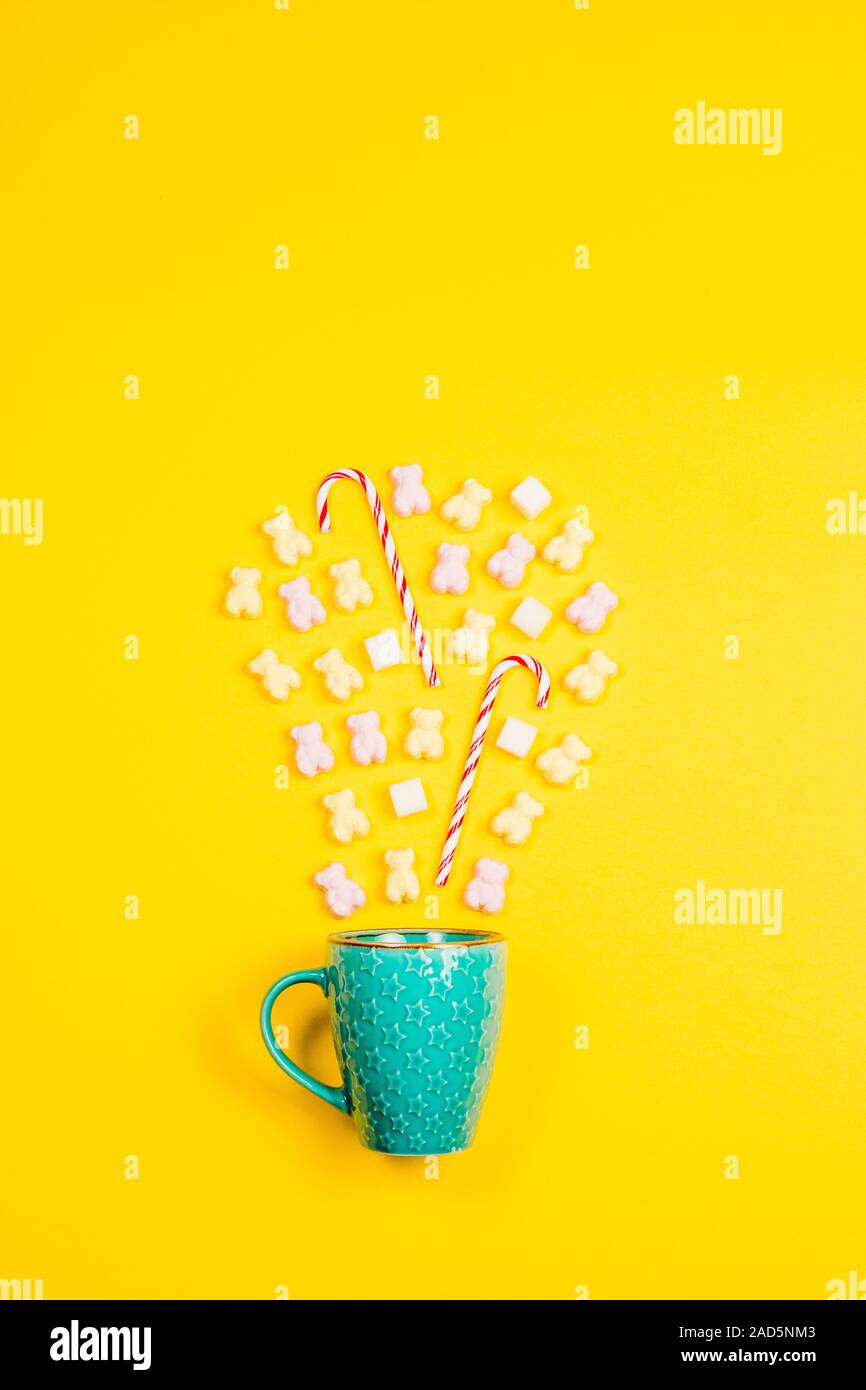Marshmallows, sugar cubes and candy sticks in a turquoise star mug on a ...