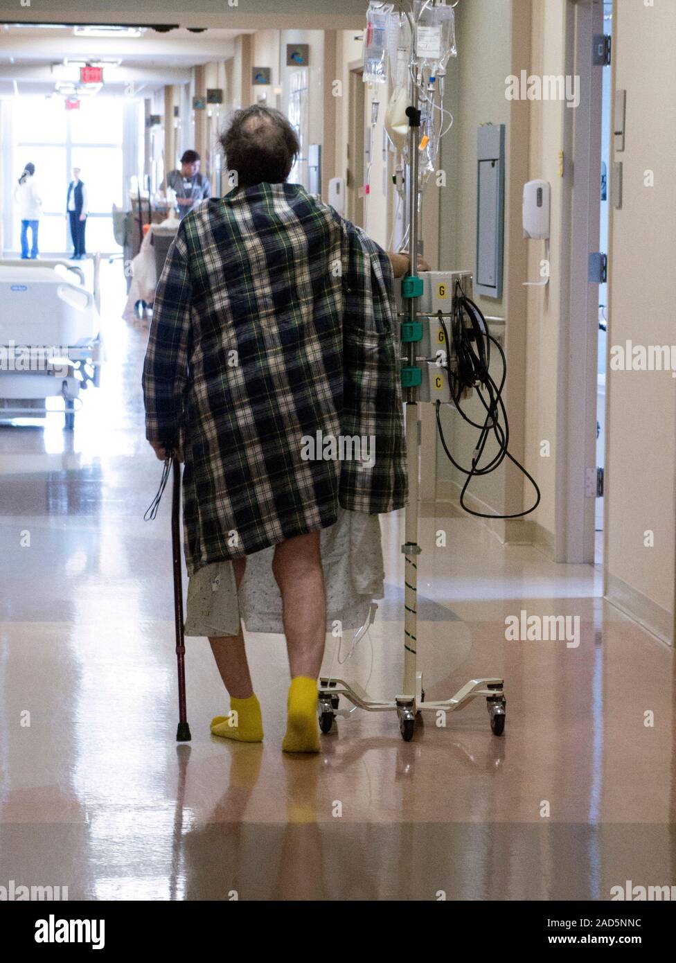 Patient walking in a hospital corridor, with a mobile IV (intravenous ...