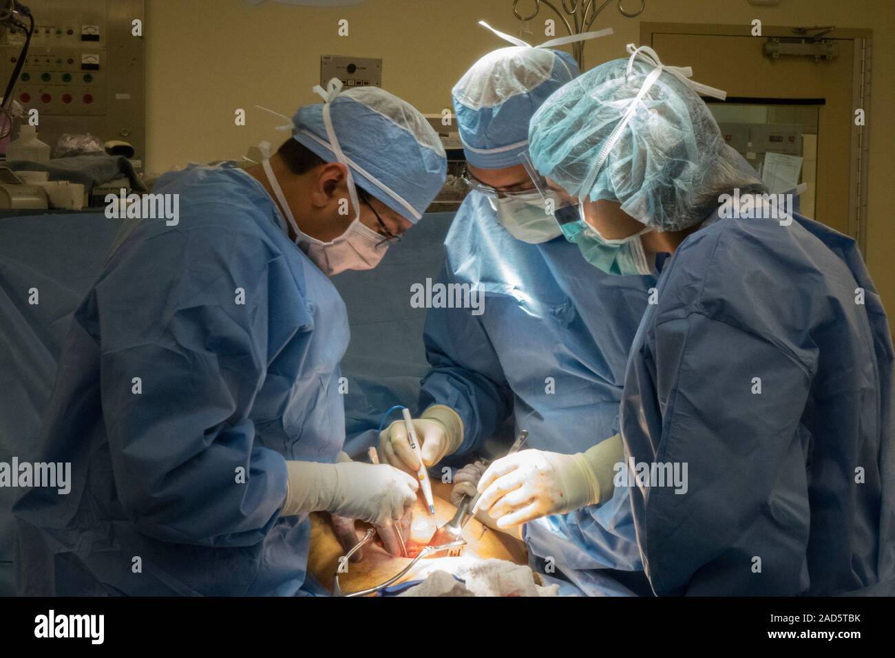 Scrotal hernia surgery. Surgeons operating on a male patient undergoing ...