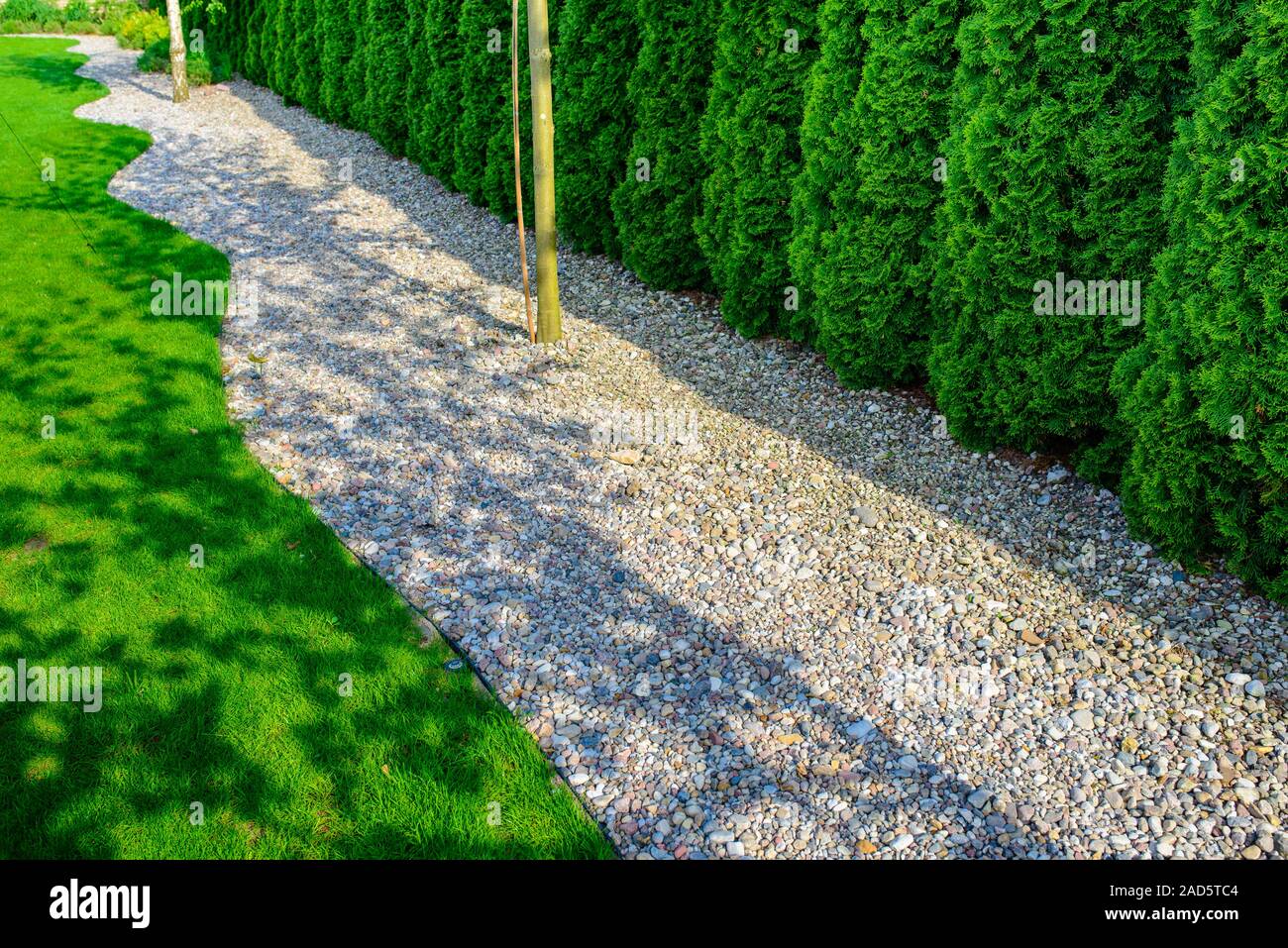 Well maintained formal garden with a paths of small stones, hedgerow ...