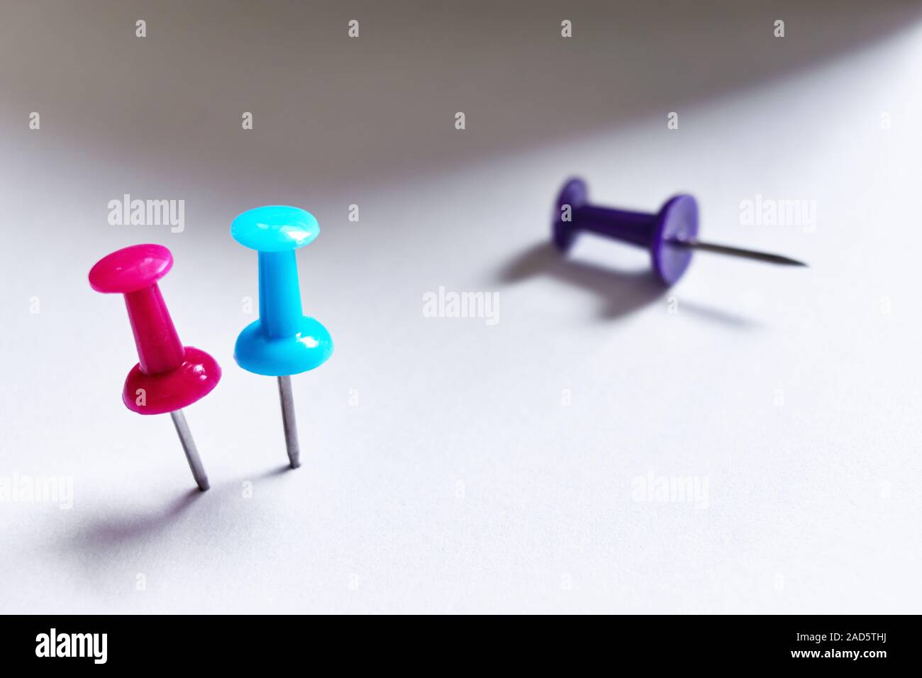 Close-up of two standing blue and red colored push pins and one ...