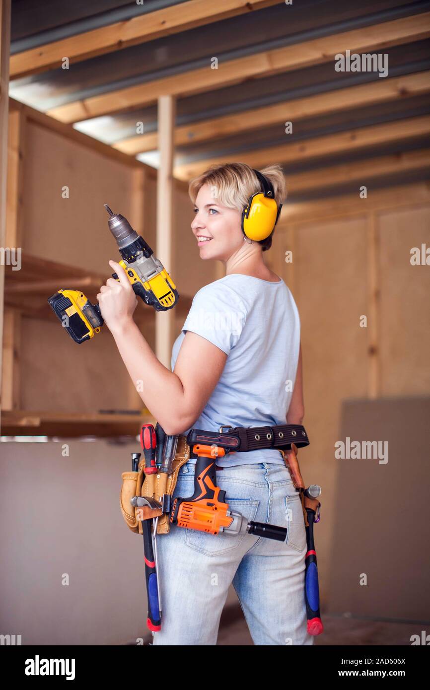 Handy woman with short hair with headphones working with drill Stock ...