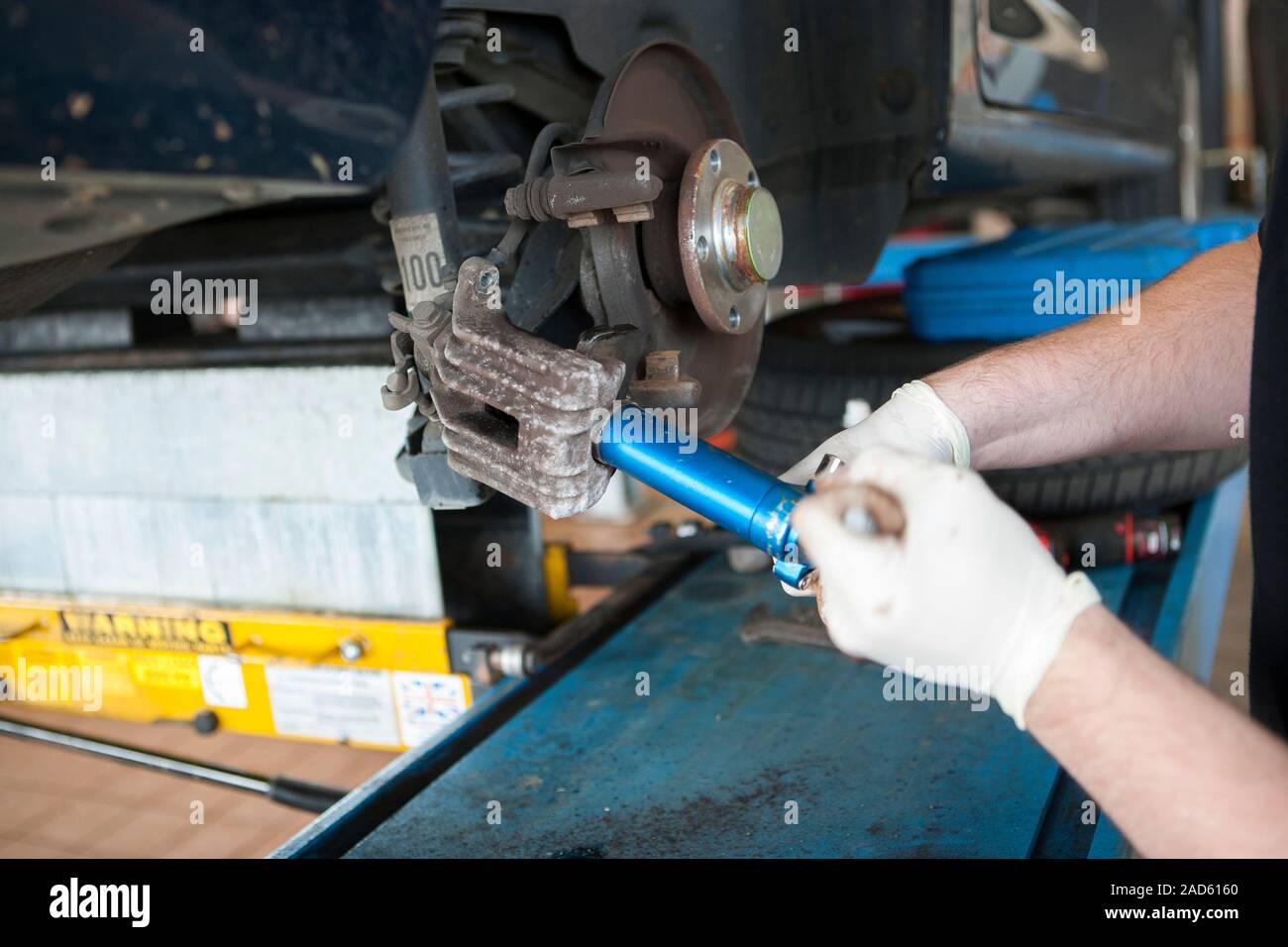 Car servicing. Technician using a hydraulic brake piston compression ...