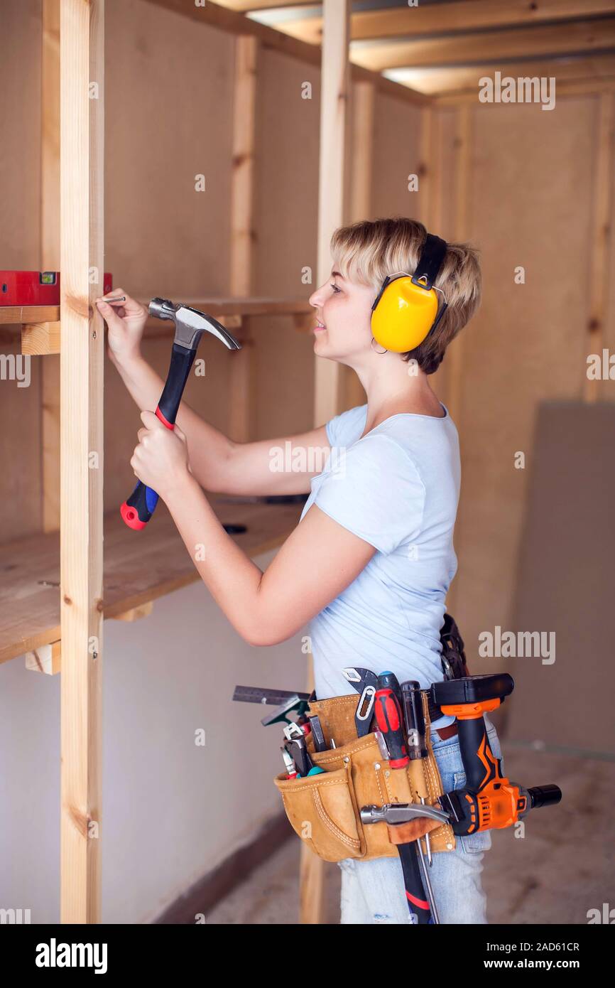 Handy woman with short hair with headphones working with hammer Stock ...