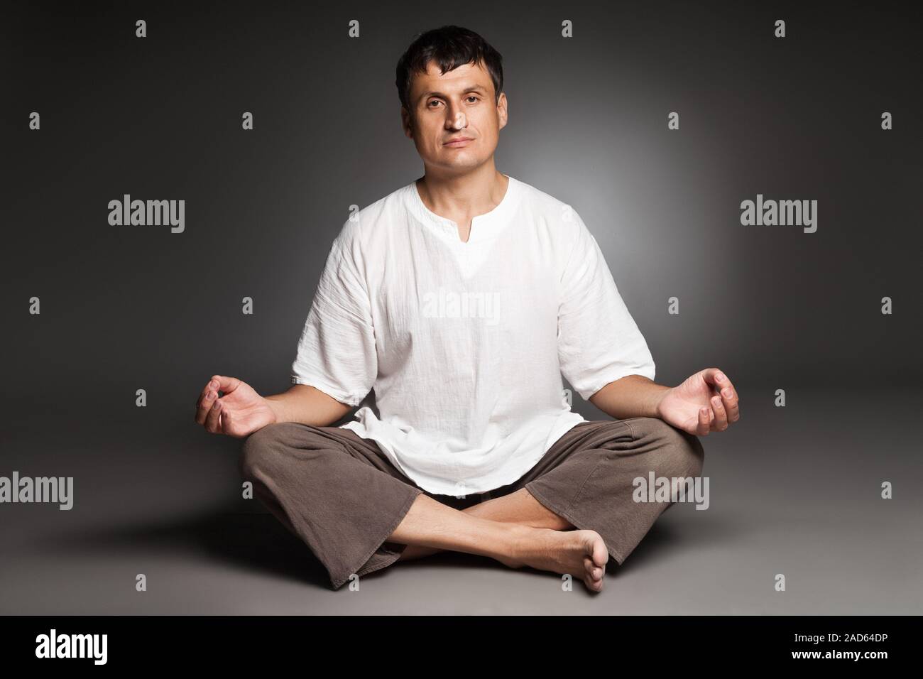 Peaceful man meditating isolated over dark Stock Photo - Alamy