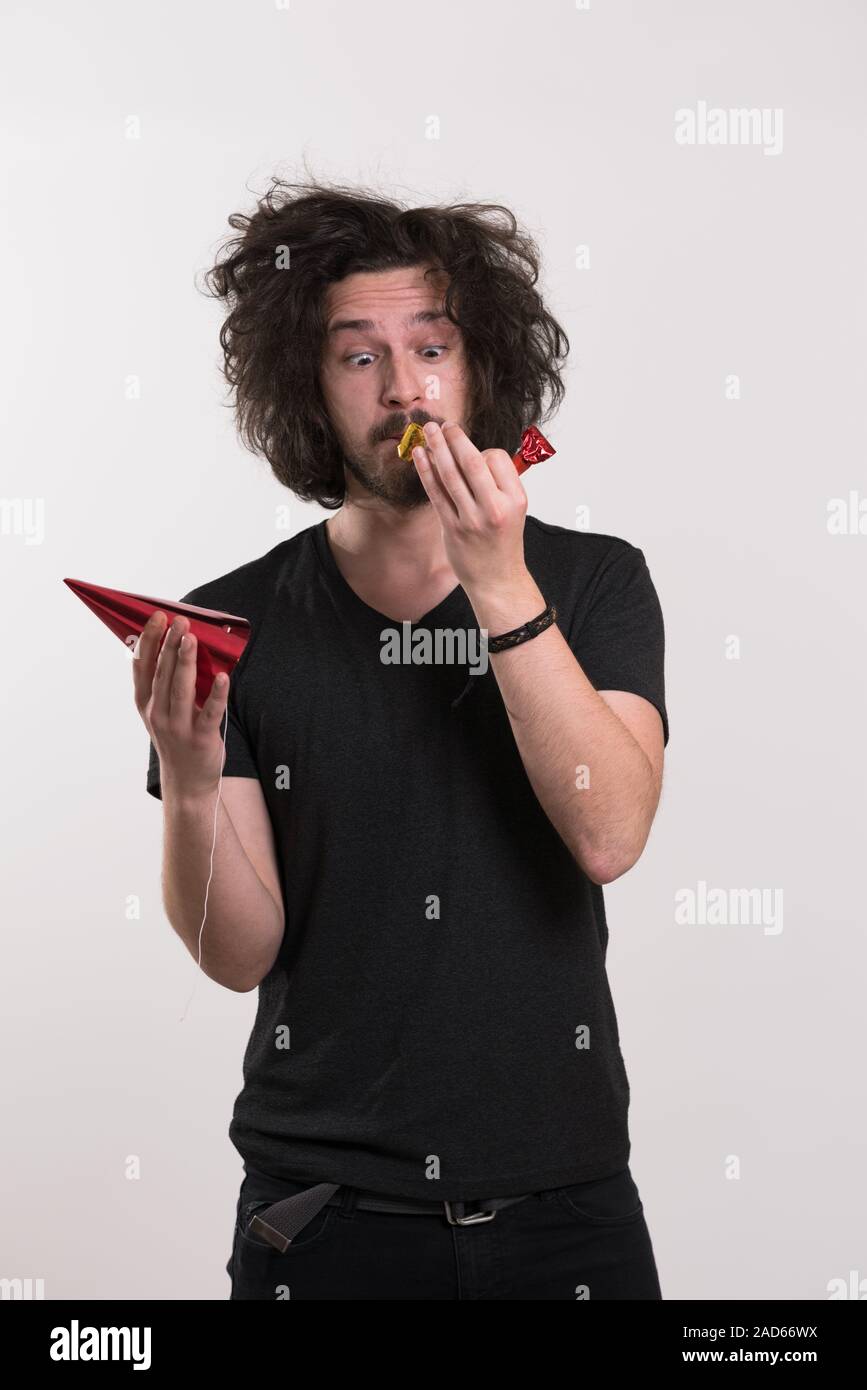 Portrait of a man in party hat blowing in whistle Stock Photo - Alamy