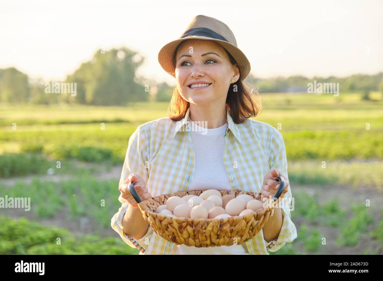 Rustic portrait of mature woman with basket of eggs at meadow Stock ...