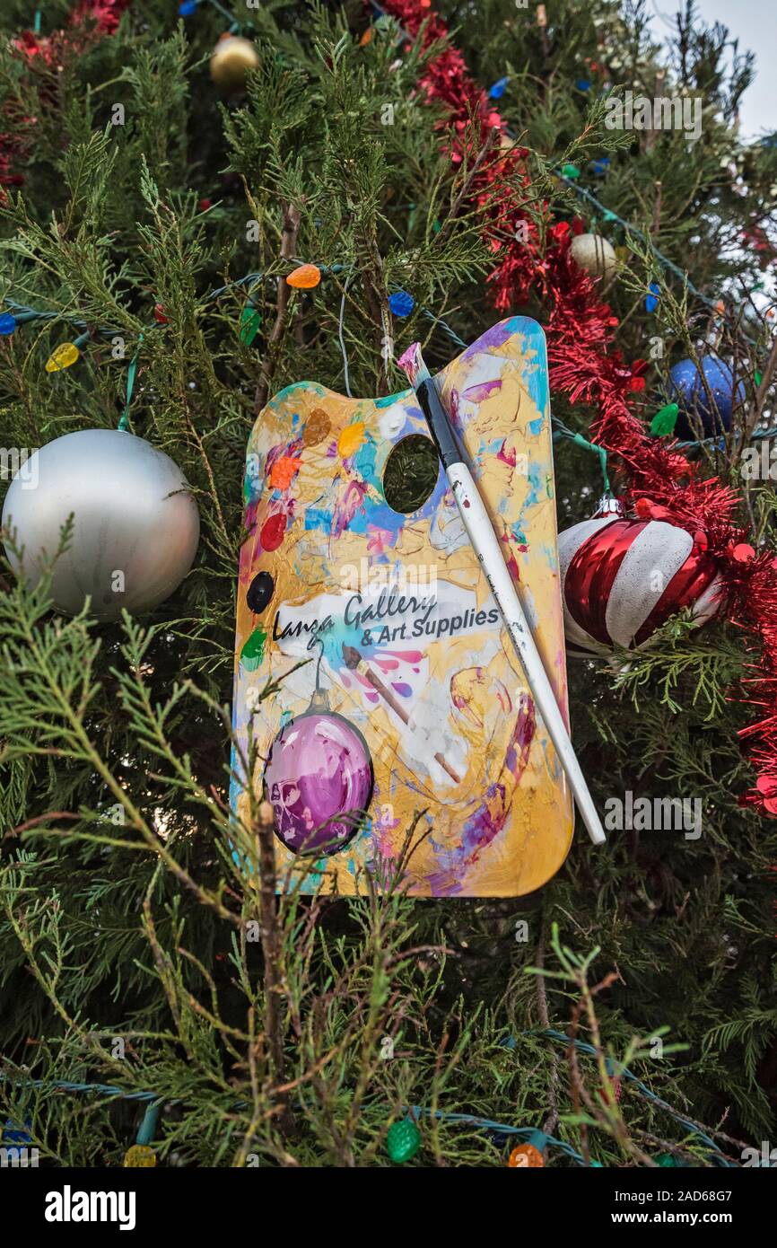 Christmas tree ornaments and gifts adorn a large outdoor community tree ...