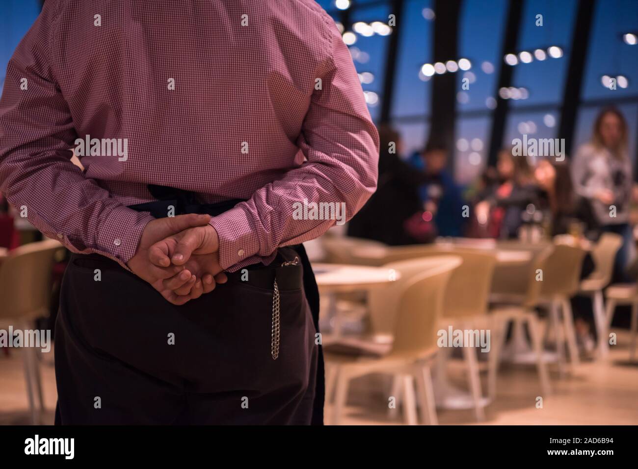 waiter standing with hands behind his back Stock Photo - Alamy