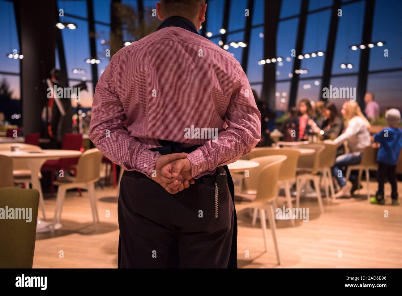 waiter standing with hands behind his back Stock Photo - Alamy