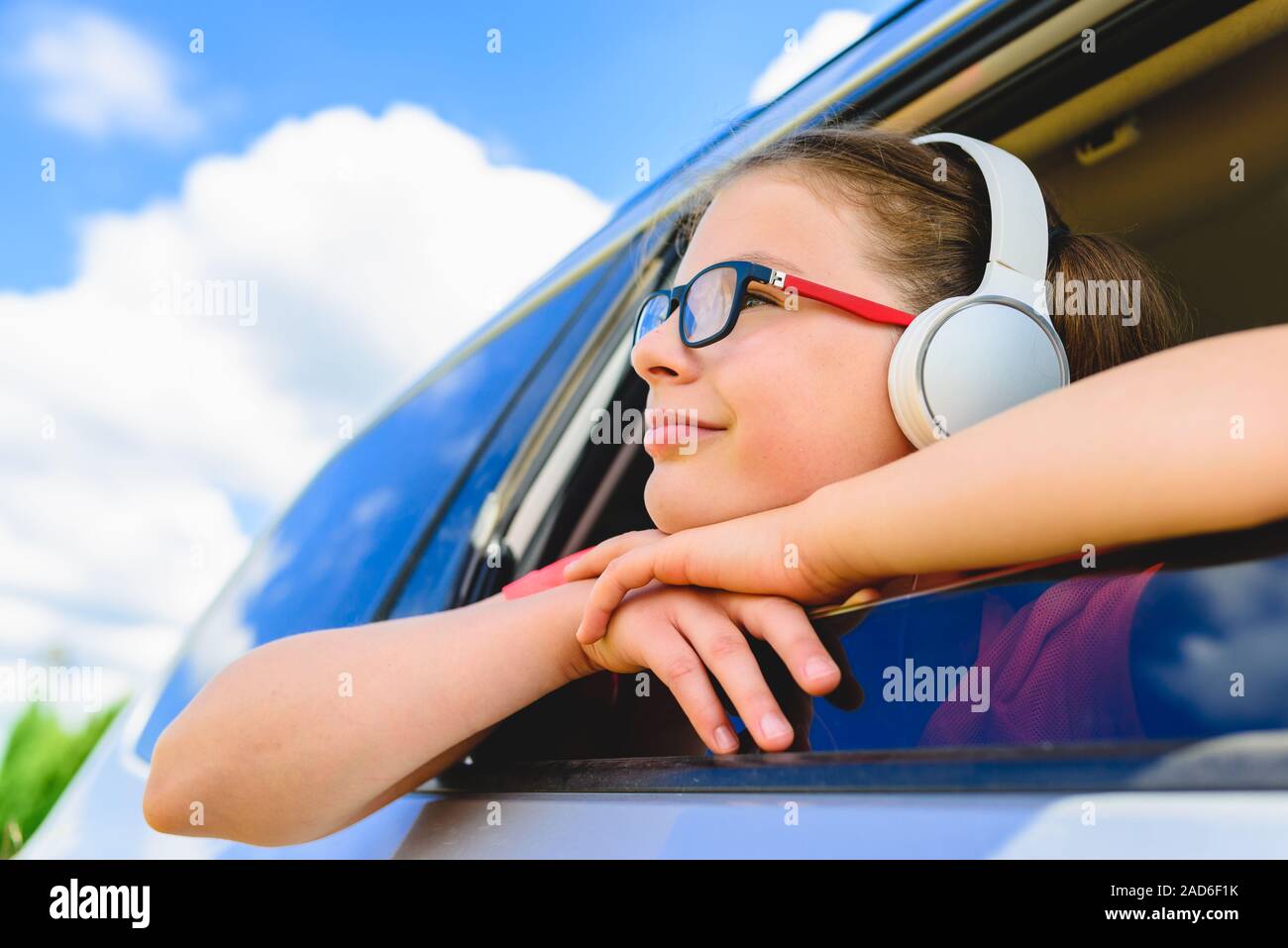 Cute girl listening to music with headphones - looking through open ...