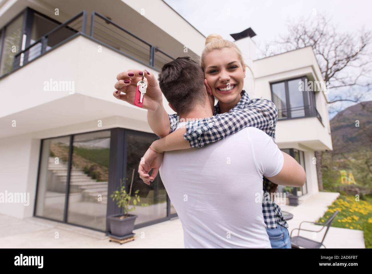 couple hugging in front of new luxury home Stock Photo - Alamy