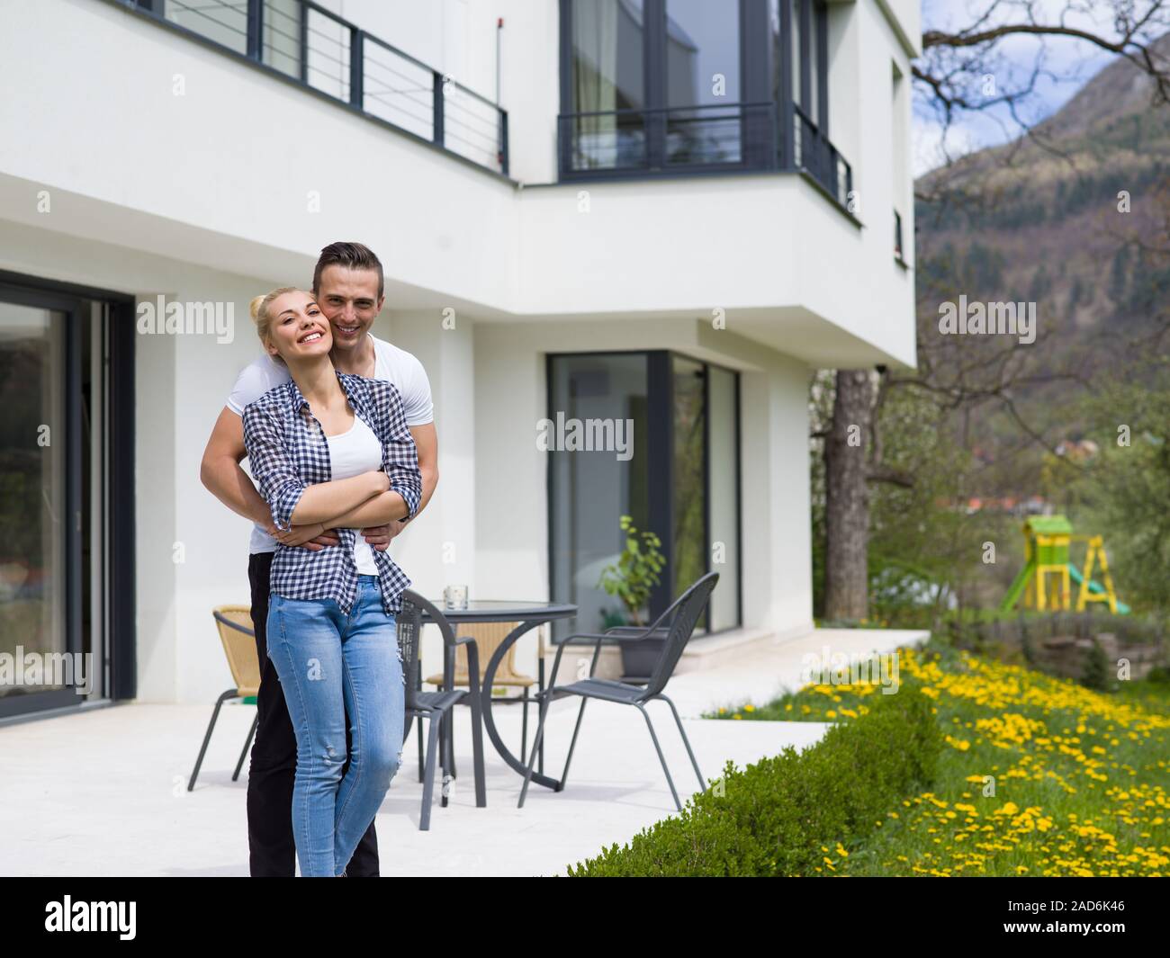couple hugging in front of new luxury home Stock Photo - Alamy