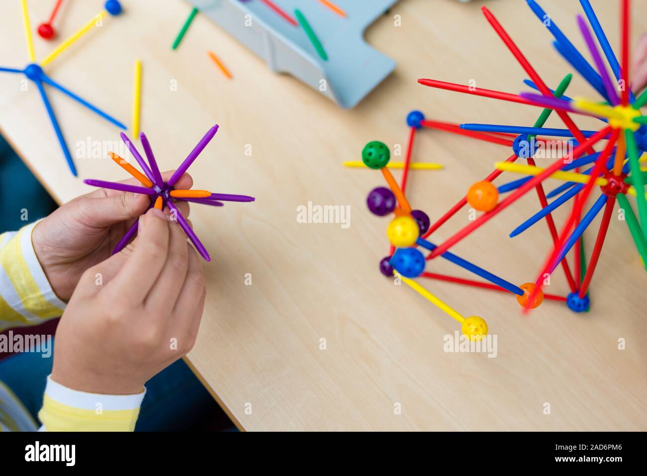 Two little girls playing with lots of colorful plastic sticks kit ...