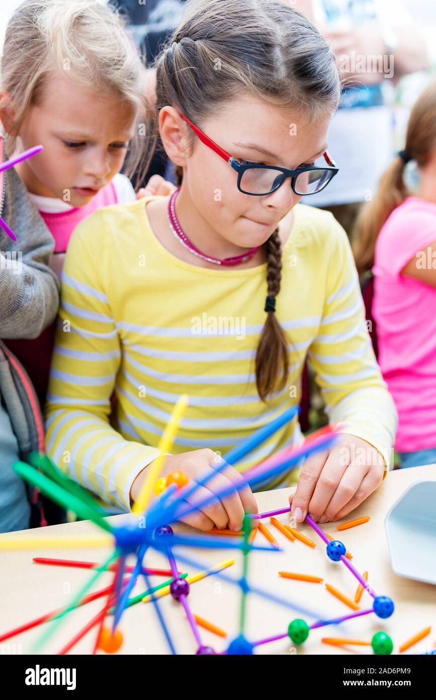 Two little girls playing with lots of colorful plastic sticks kit ...
