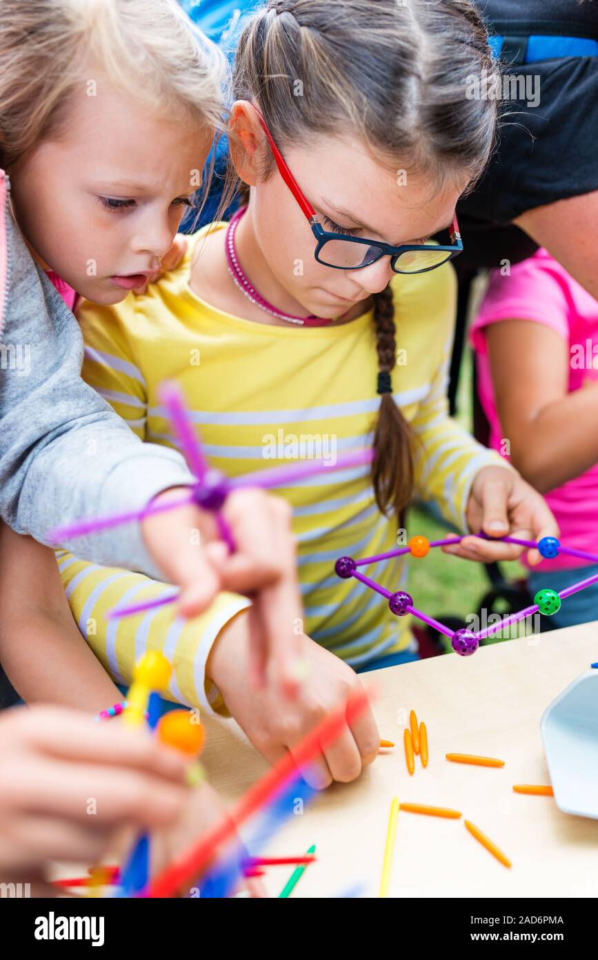 Two little girls playing with lots of colorful plastic sticks kit ...