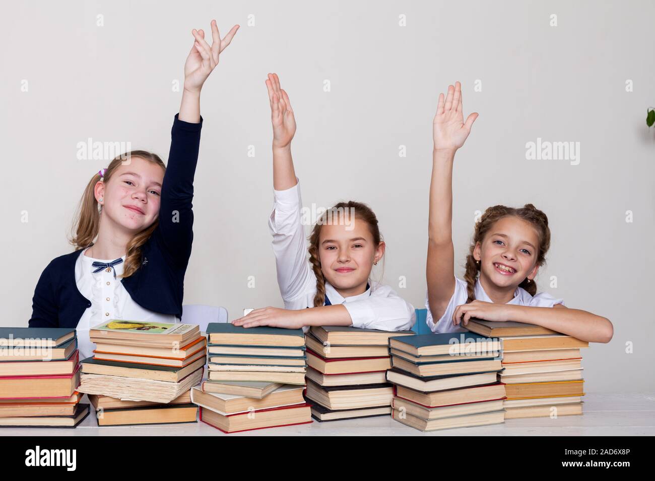 three girls of school girls with books for study sit at the desk in the ...