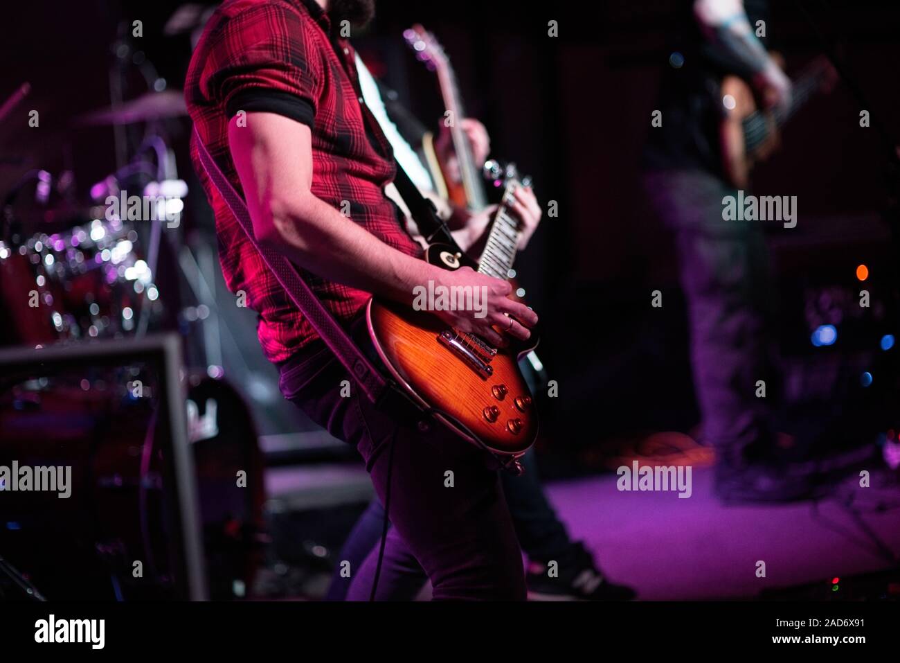 Rock band performs on stage. Guitarist, bass guitar and drums. The ...