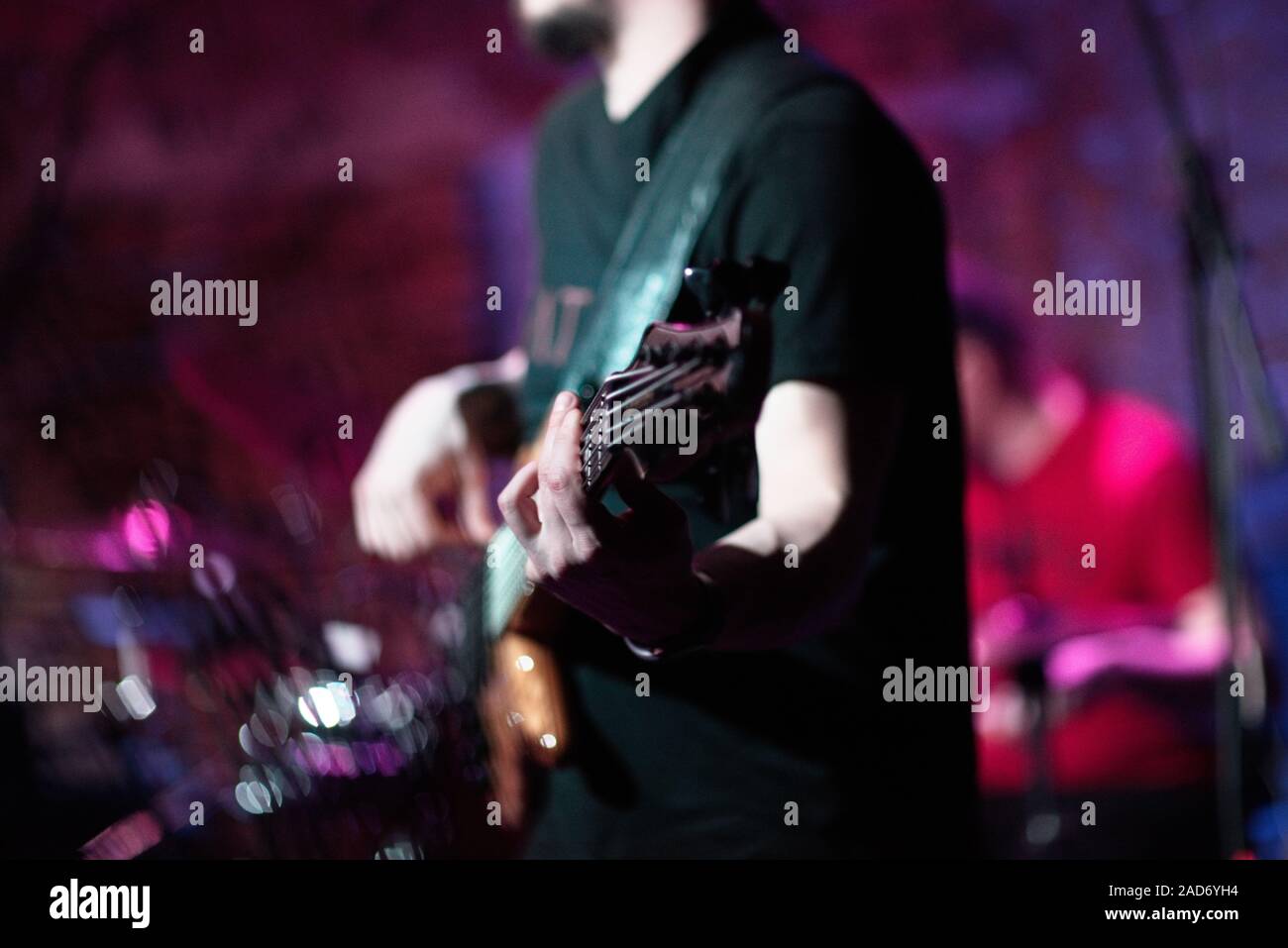 Rock band performs on stage. Guitarist, bass guitar and drums. The ...