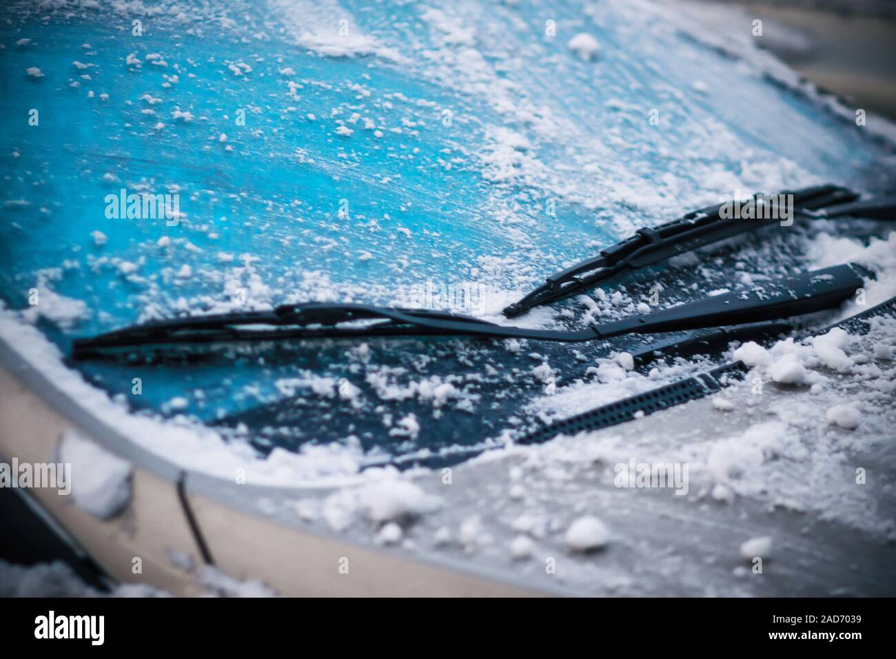 In cold snowy winter weather, the car cleans its windshield, covered ...