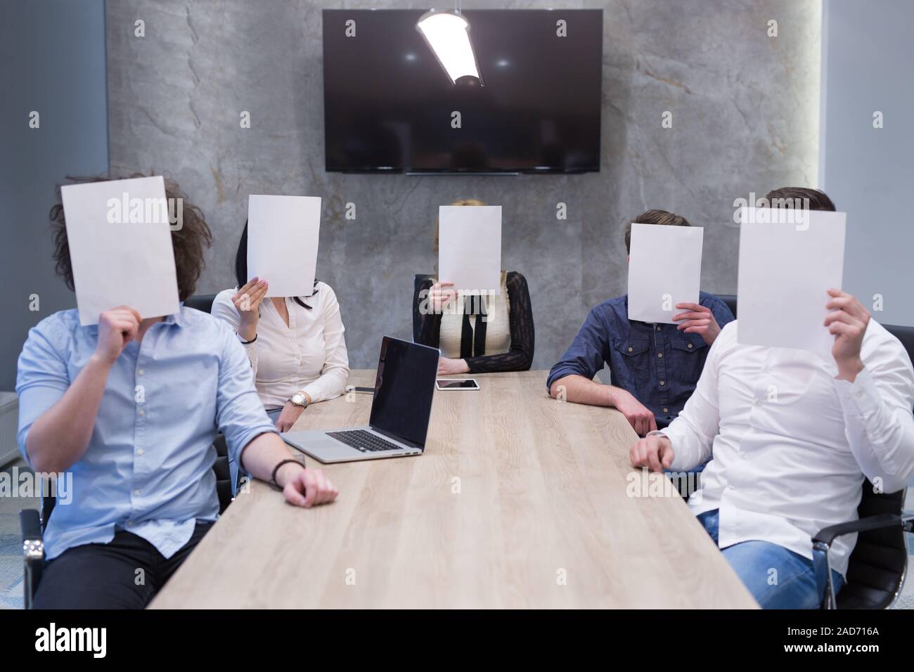 startup Business team holding a white paper over face Stock Photo - Alamy