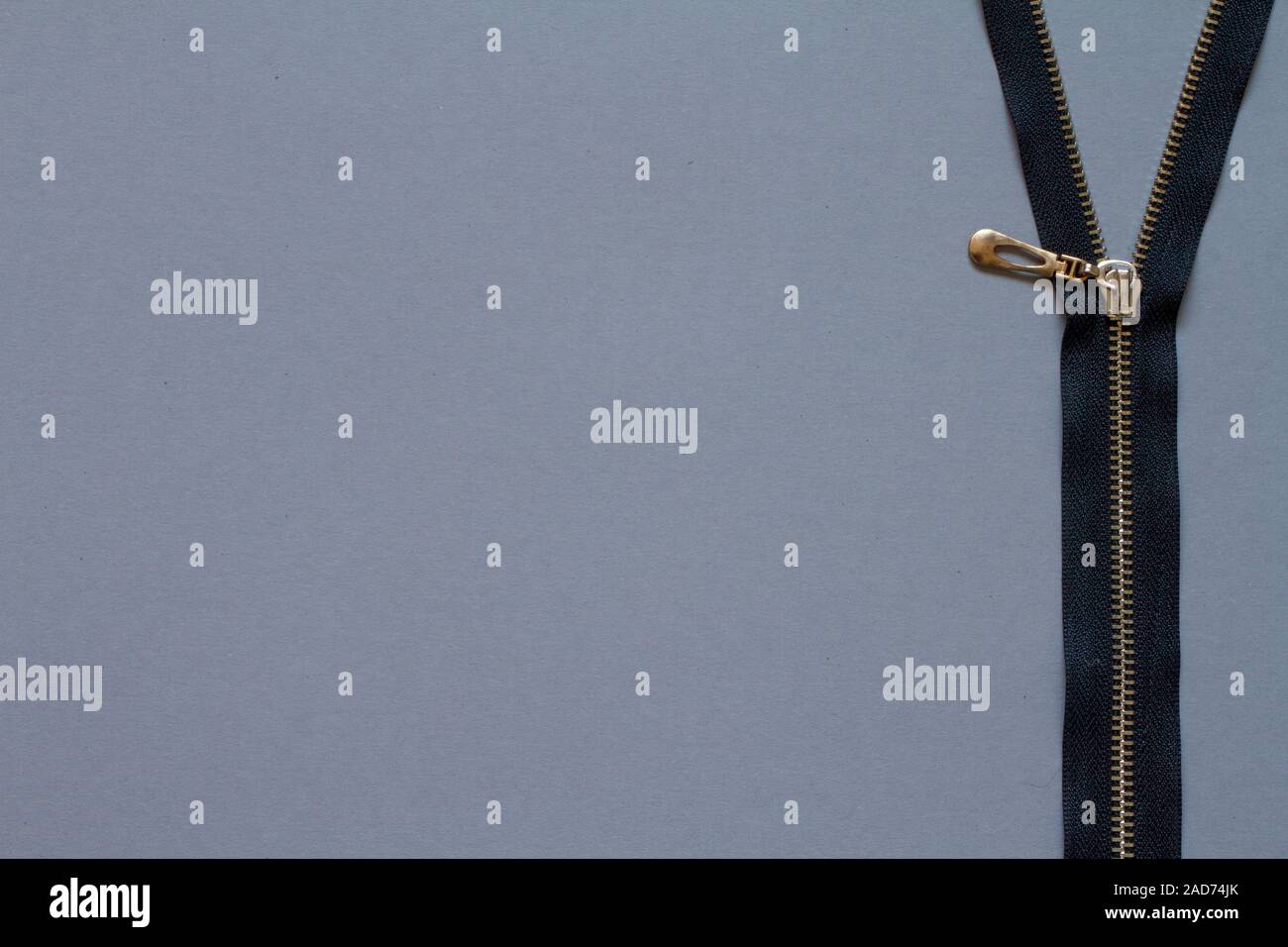 Open zipper clasp with a golden slider on a gray background ...