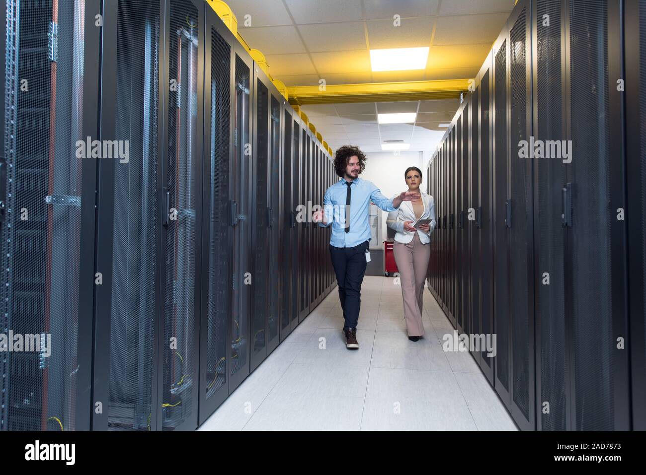 engineer showing working data center server room to female chief Stock ...