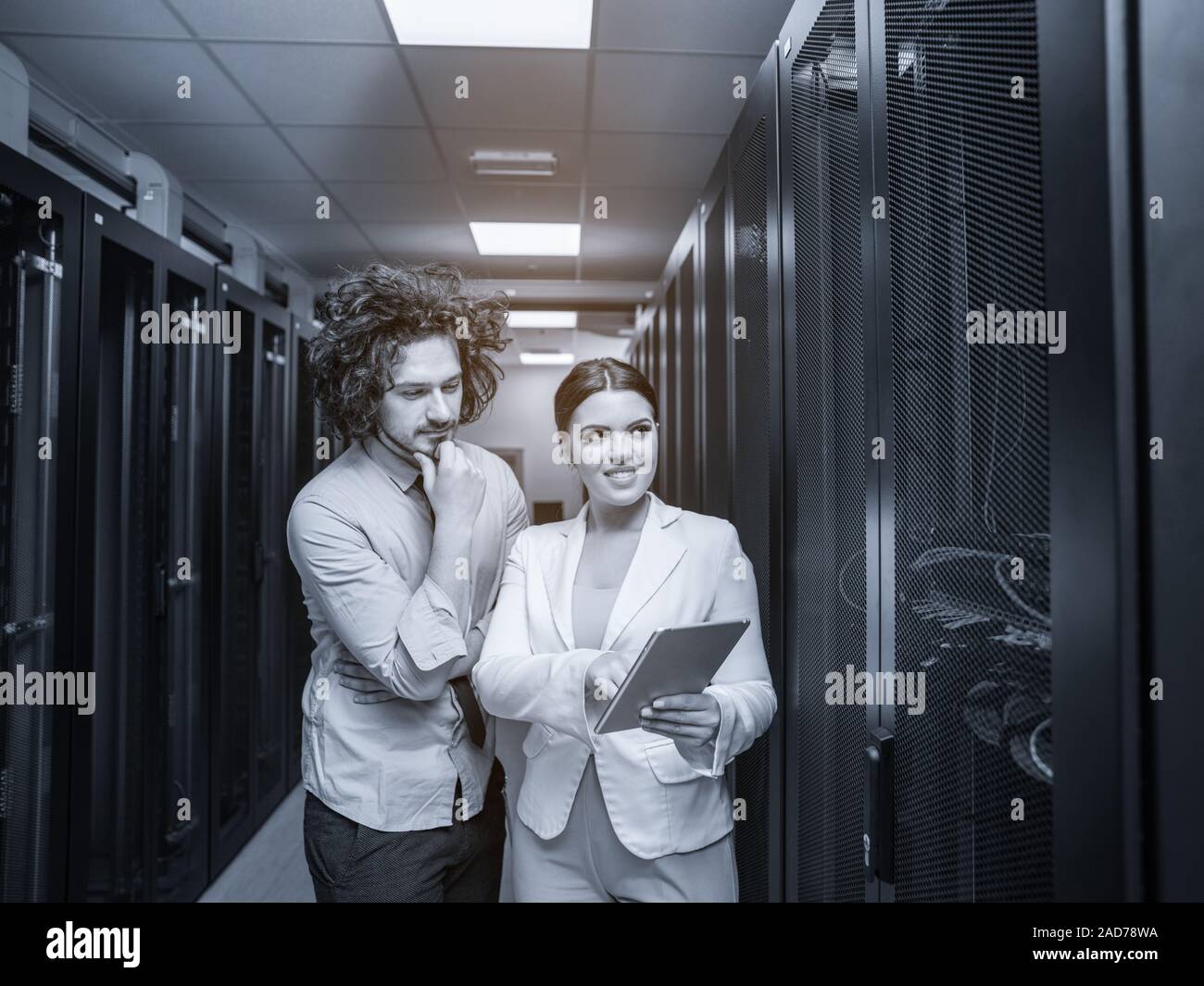 engineer showing working data center server room to female chief Stock ...
