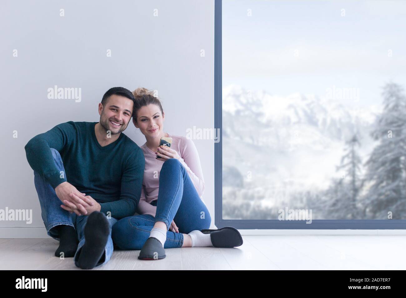young couple sitting on the floor near window at home Stock Photo - Alamy