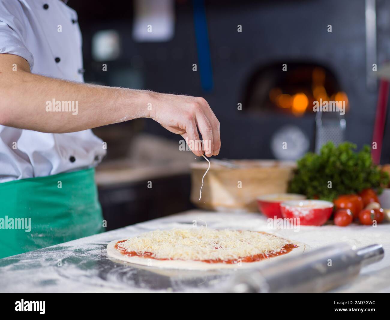 chef sprinkling cheese over fresh pizza dough Stock Photo - Alamy