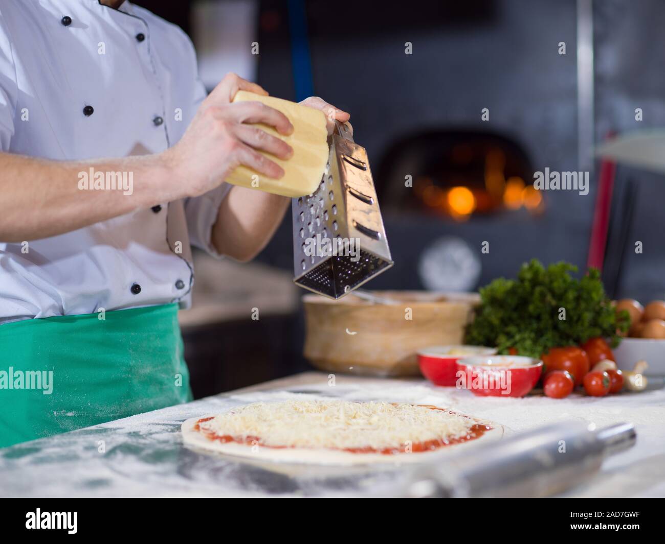 chef sprinkling cheese over fresh pizza dough Stock Photo - Alamy