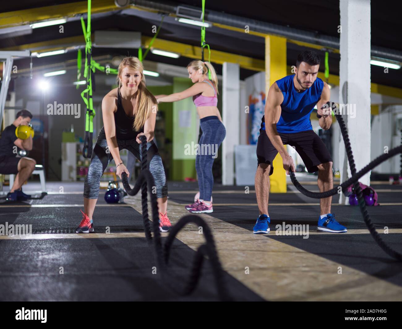 sports couple doing battle ropes crossfitness exercise Stock Photo - Alamy
