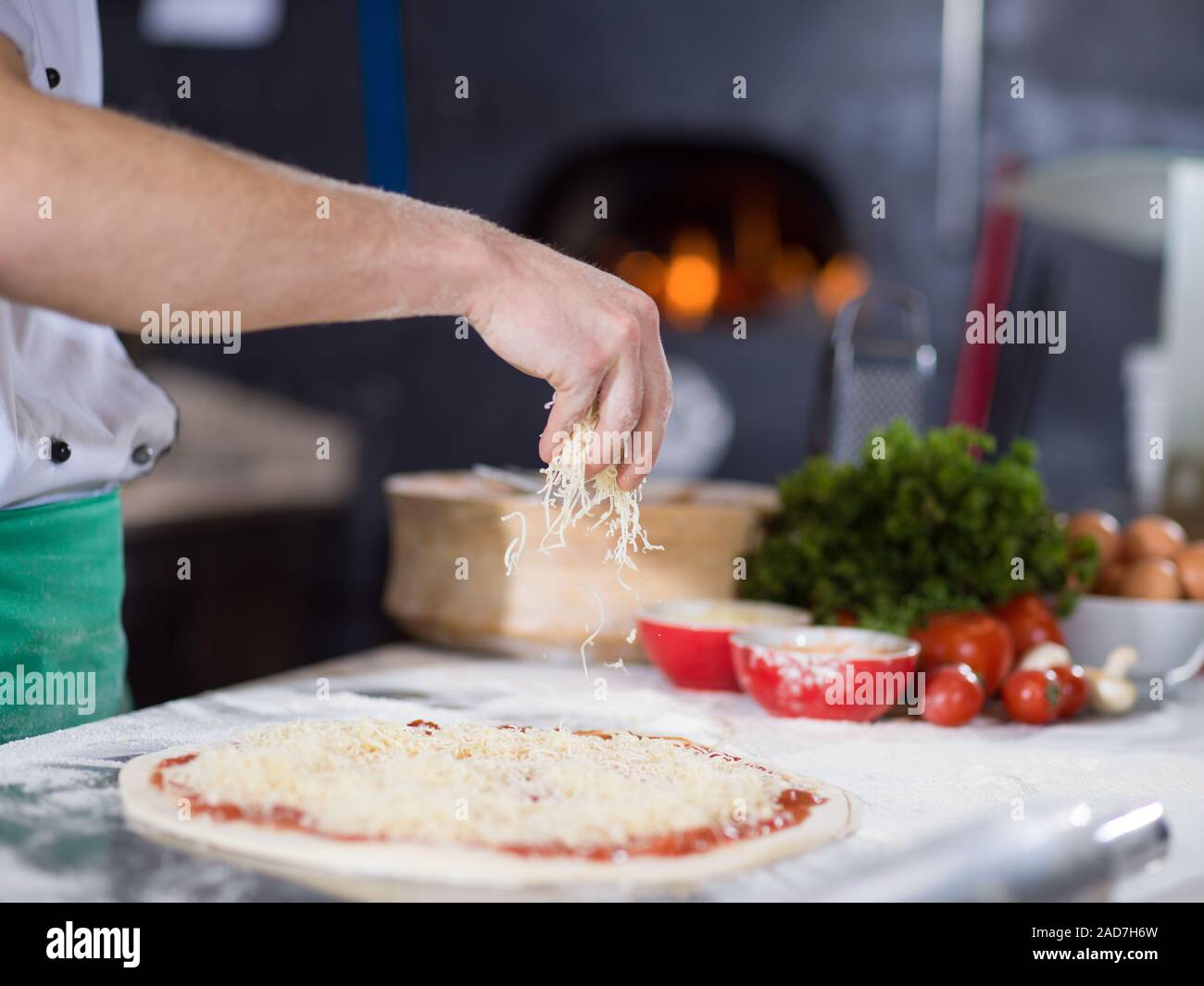 chef sprinkling cheese over fresh pizza dough Stock Photo - Alamy