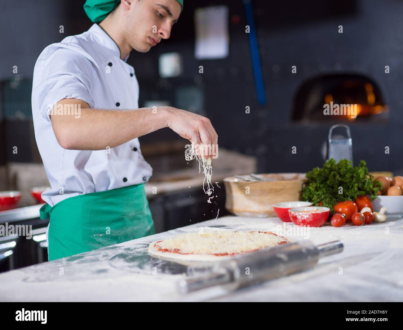 chef sprinkling cheese over fresh pizza dough Stock Photo - Alamy